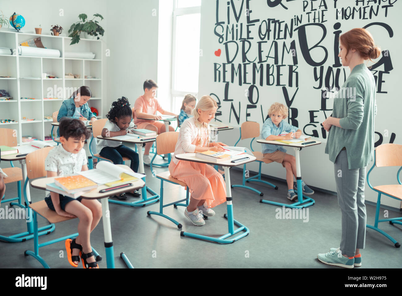 Teacher standing in front of class explaining new topic Stock Photo - Alamy