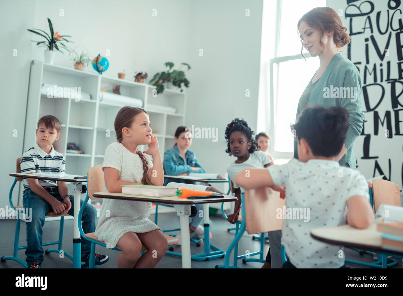 Little girl answering a question the teacher asked her Stock Photo - Alamy