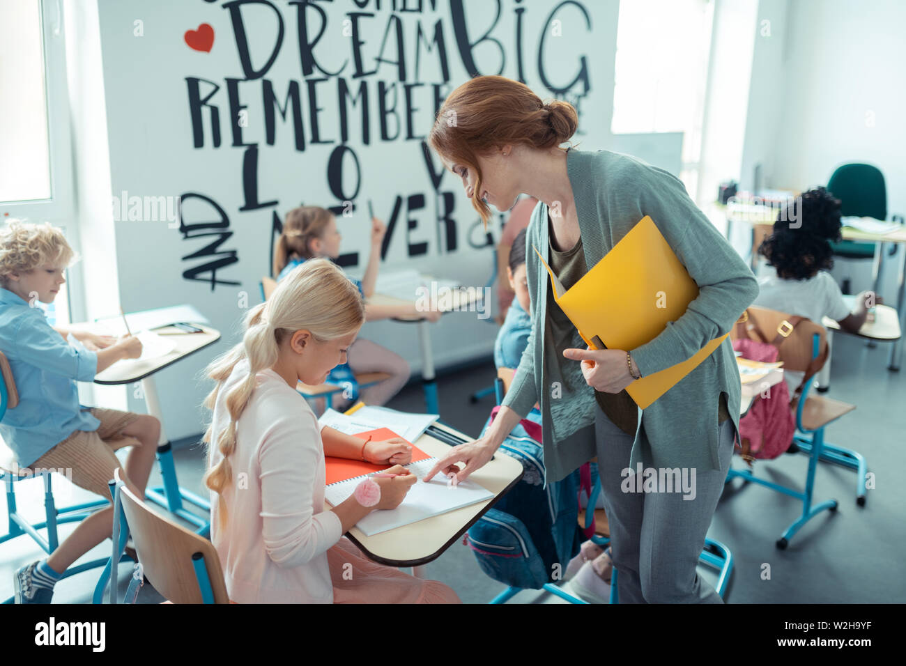 Teacher checking exercises in copybooks of her pupils Stock Photo - Alamy