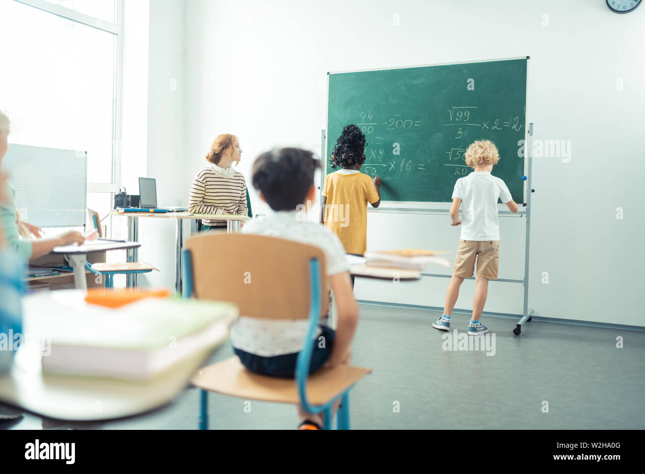 Two classmates writing together on the blackboard Stock Photo - Alamy