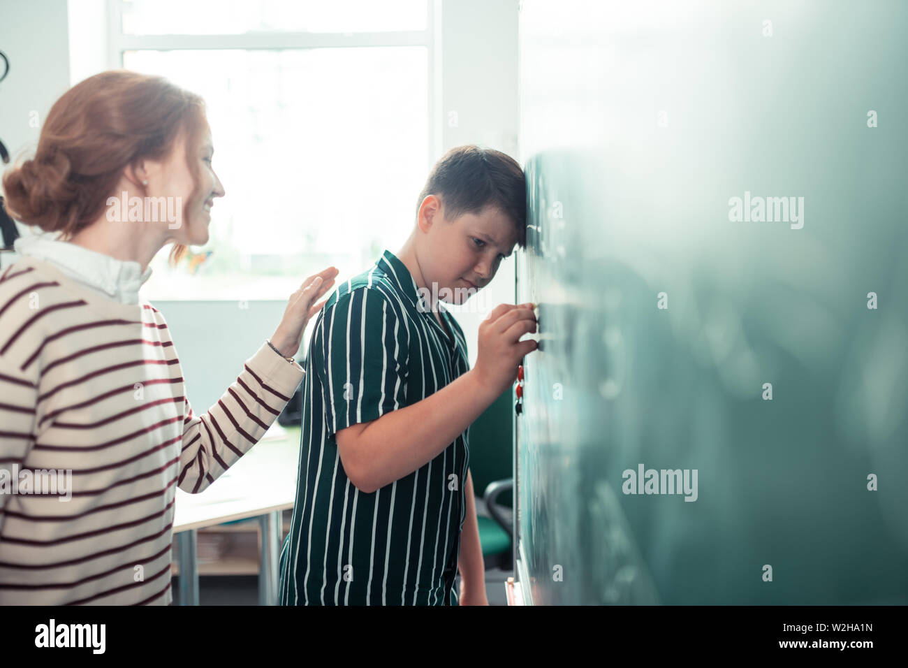 Teacher cheering up sad pupil near the blackboard Stock Photo - Alamy