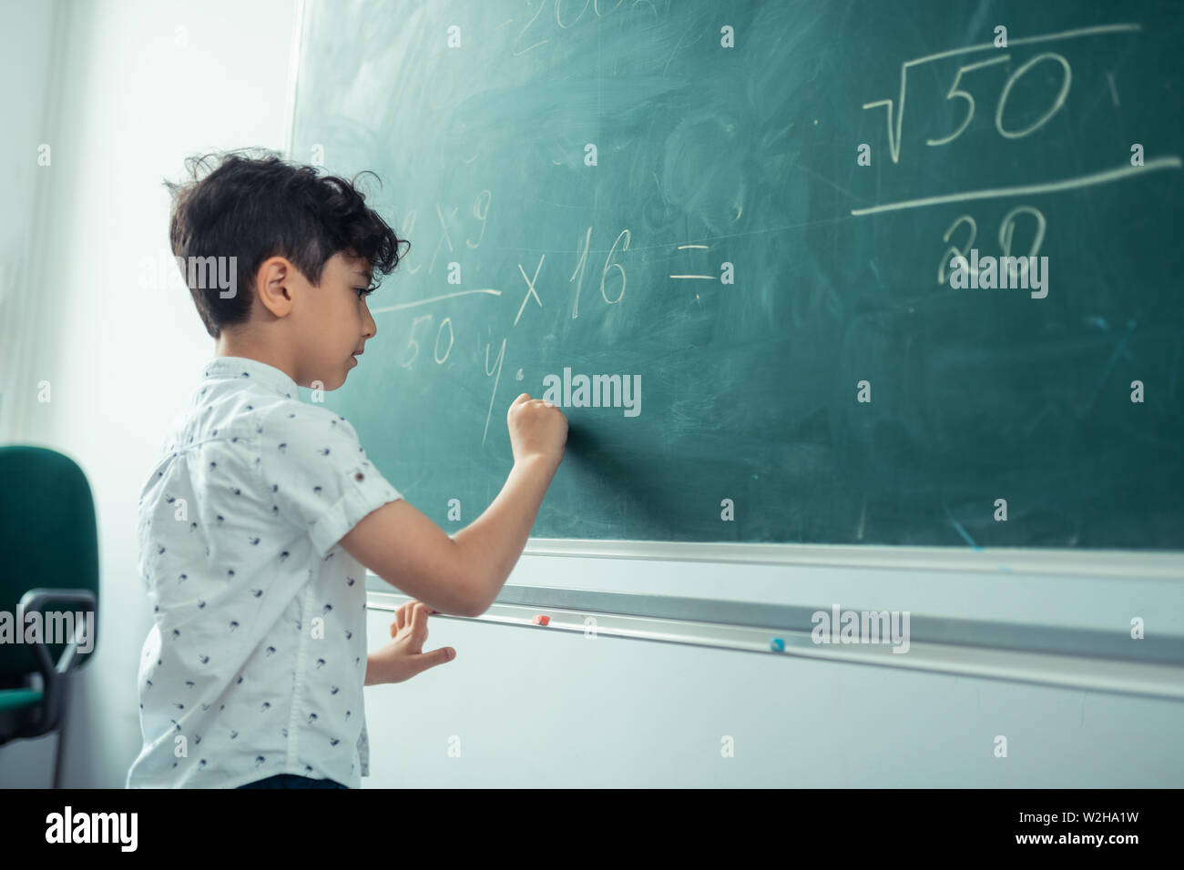 Little concentrated schoolboy writing on the blackboard Stock Photo - Alamy