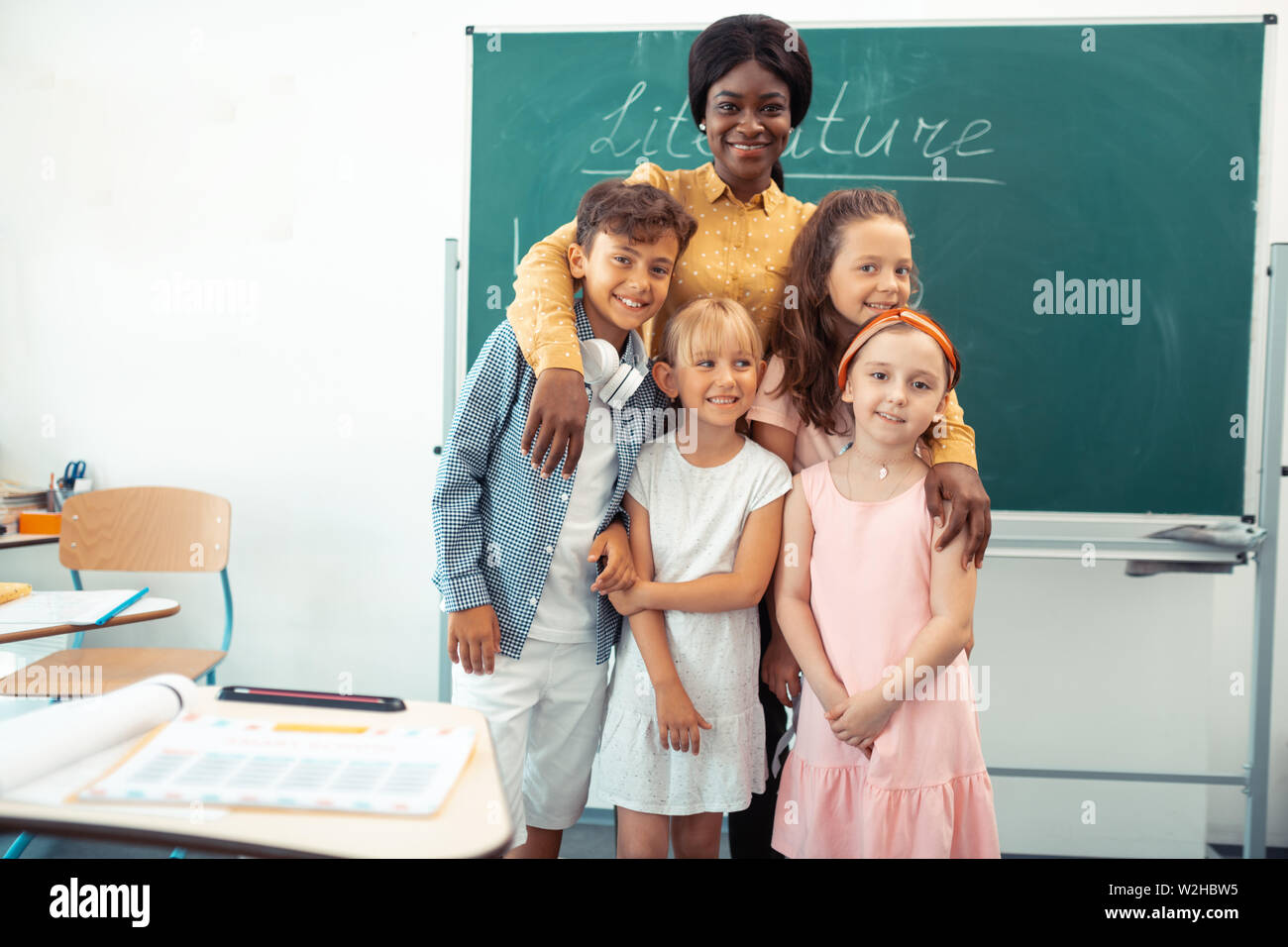 Loving happy teacher hugging her smart diligent pupils Stock Photo - Alamy