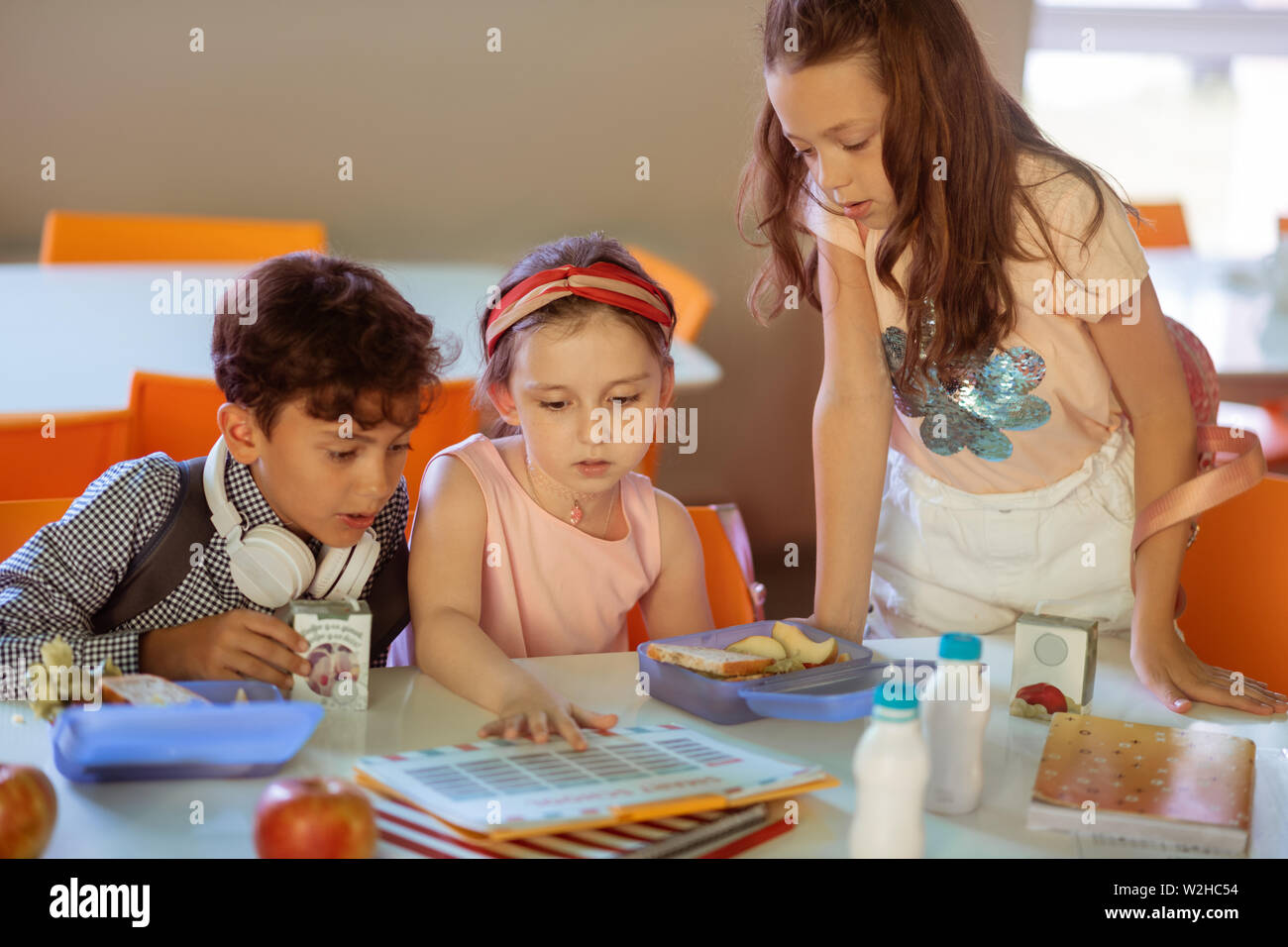 Girls and boy checking the schedule while having lunch in canteen Stock ...
