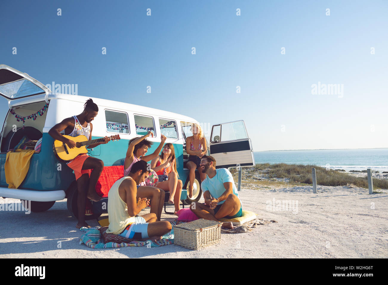 Group of friends having fun near camper van at beach Stock Photo - Alamy