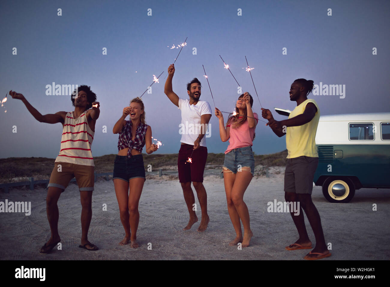 Group of friends dancing with sparklers on the beach at dusk Stock ...