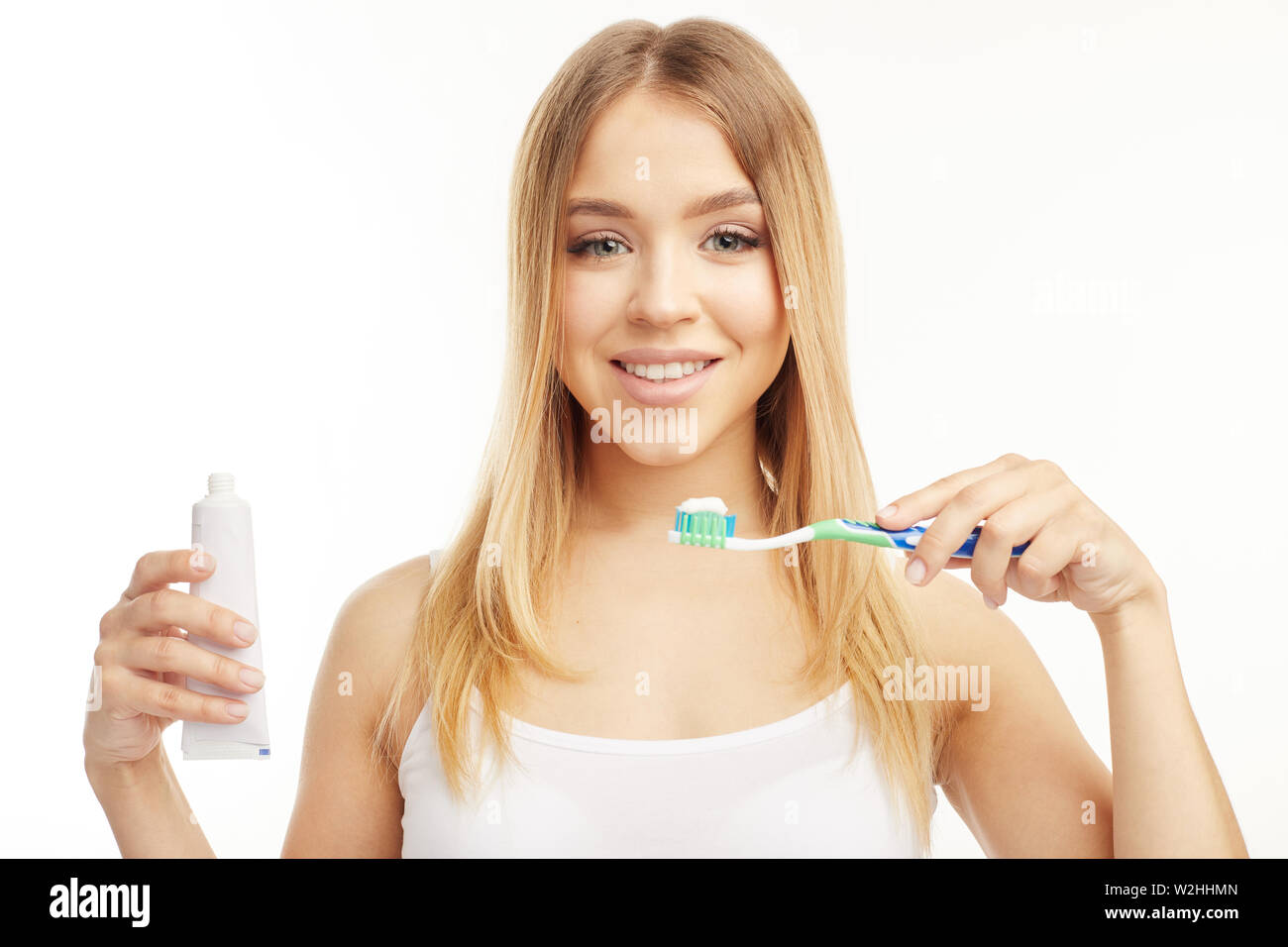 Smiling blonde on a white background showing how to use toothpaste and ...