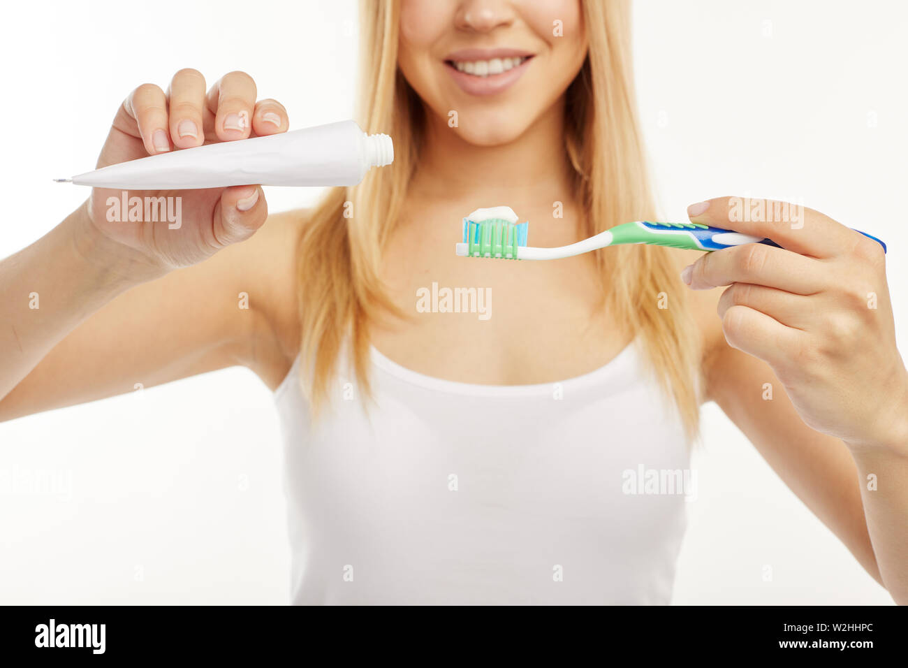 Smiling blonde on a white background showing how to use toothpaste and ...