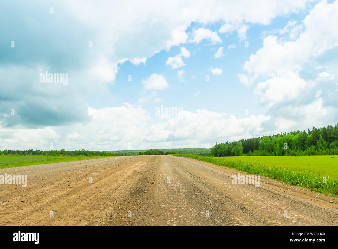 Landscape rural road and blue sky. Straight gravel road leading to the ...