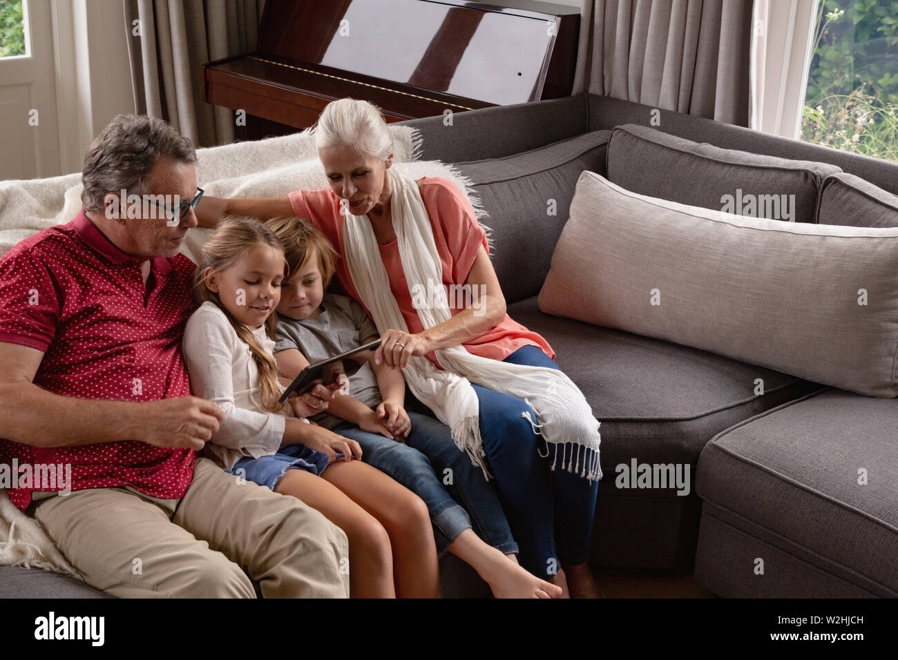 Multi-generation family using digital tablet on sofa in a comfortable ...