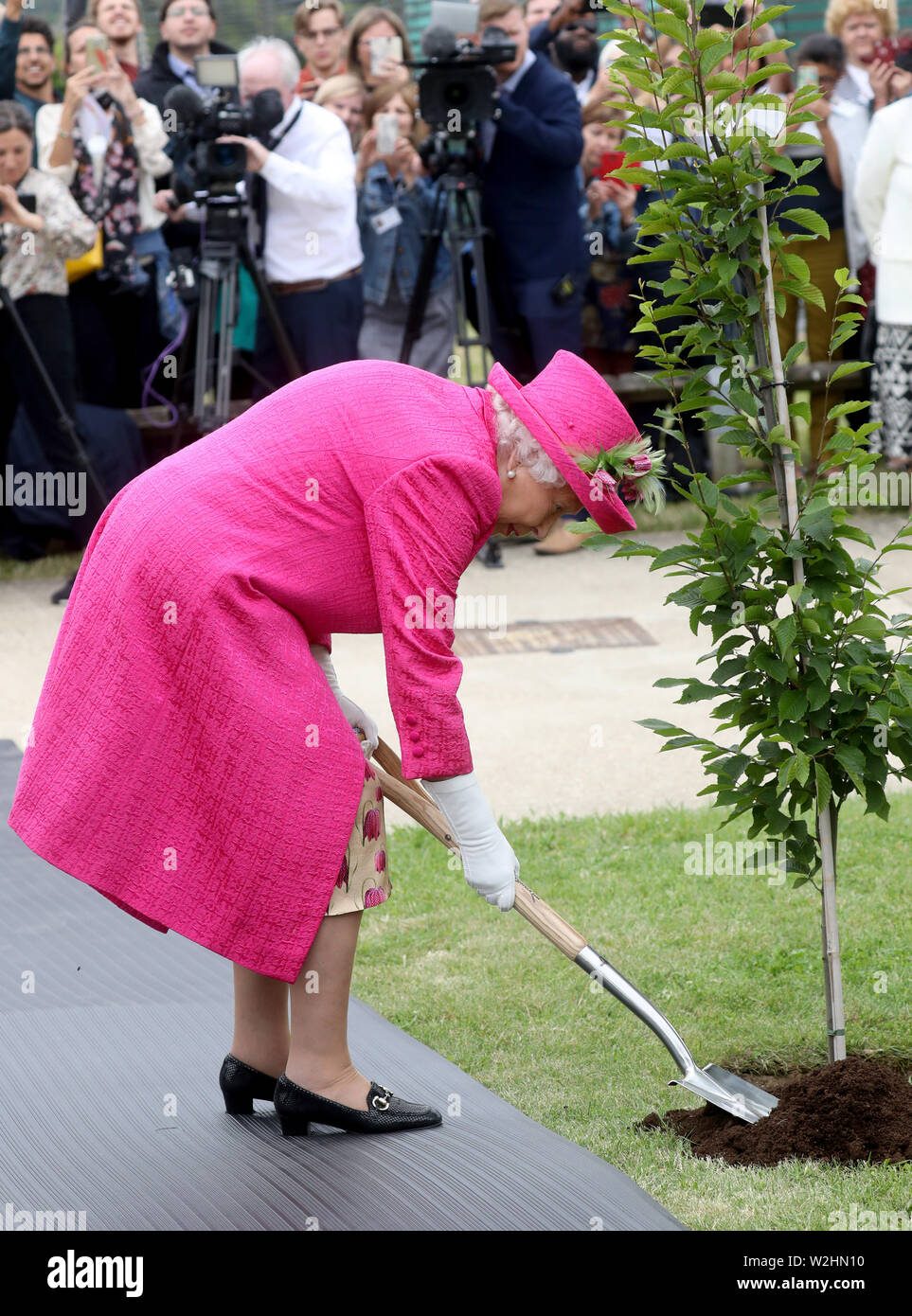 Queen Elizabeth II plants a tree during a visit to the National ...