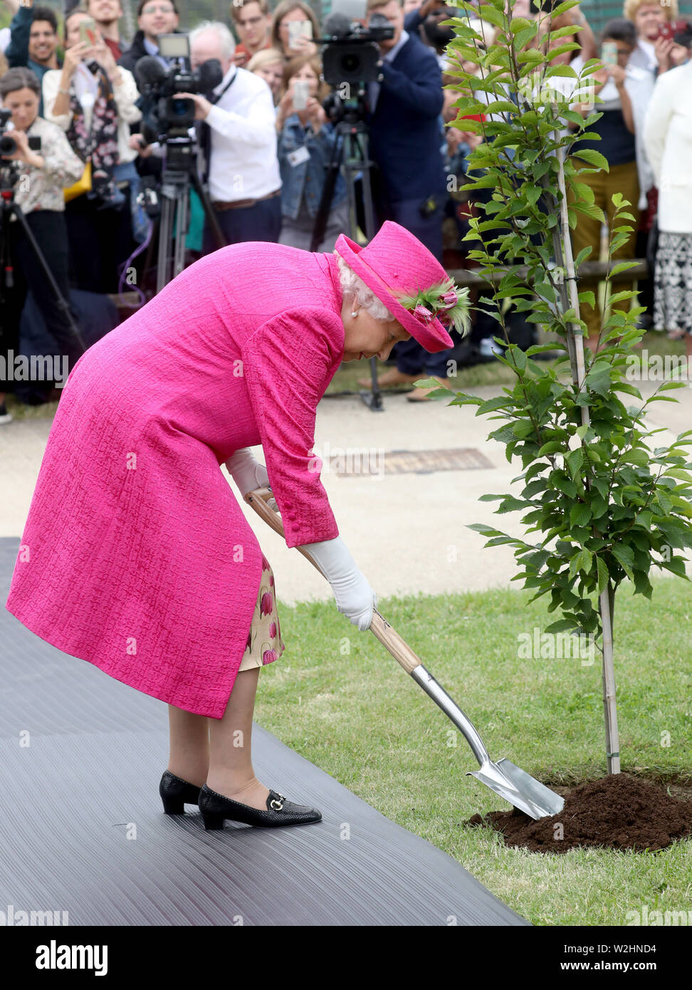 Queen Elizabeth II plants a tree during a visit to the National ...