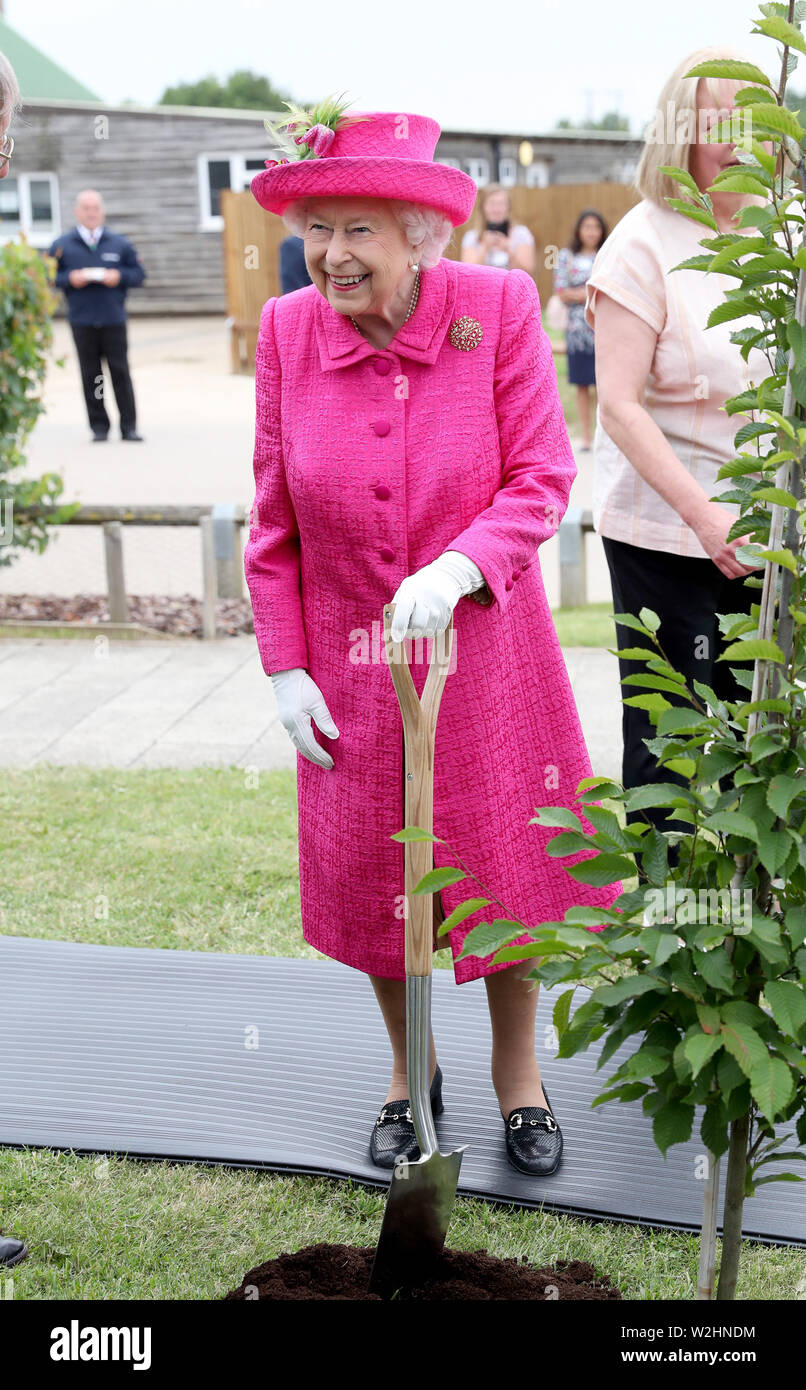 Queen Elizabeth II plants a tree during a visit to the National ...