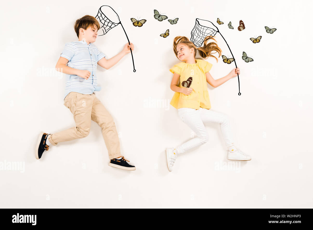 top view of cheerful kids with butterfly nets smiling near butterflies ...