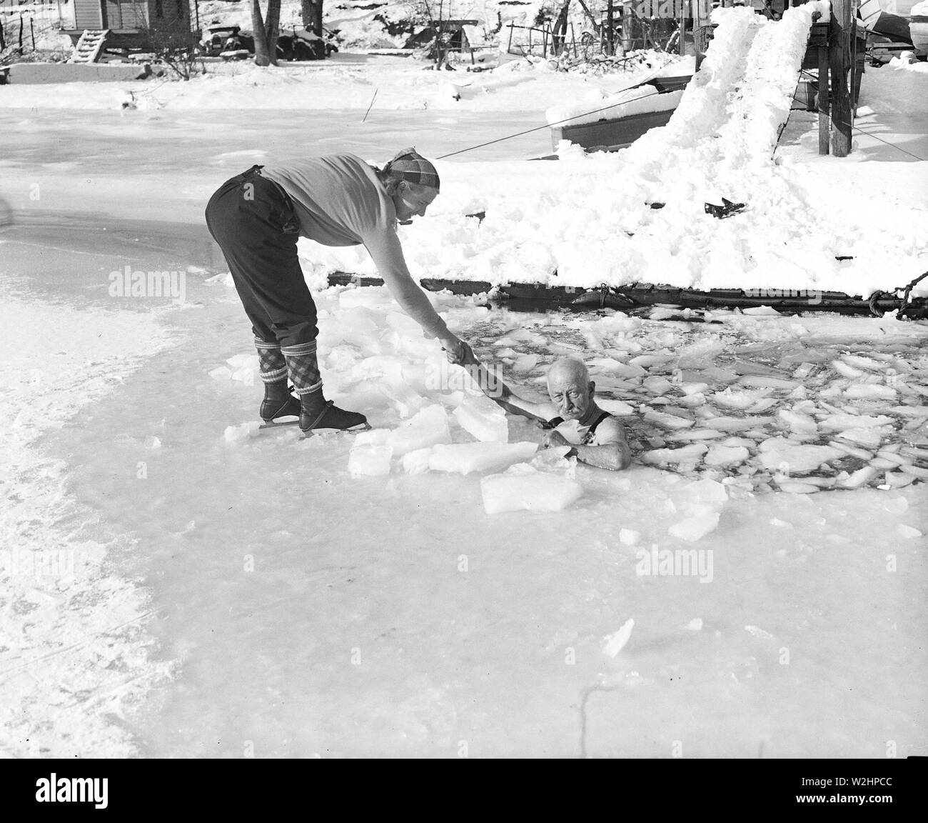 Female Skater helping man in ice water ca. 1934 Stock Photo - Alamy