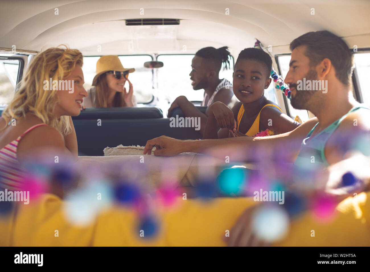 Group of friends talking with each other in a camper van at beach Stock ...
