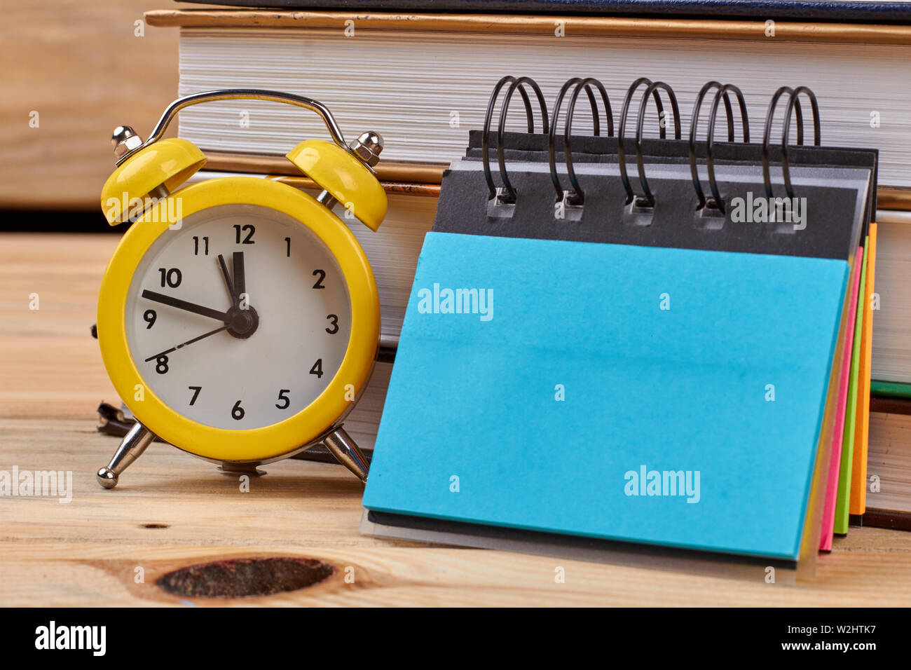 Alarm clock, spiral notebook and stack of books Stock Photo - Alamy