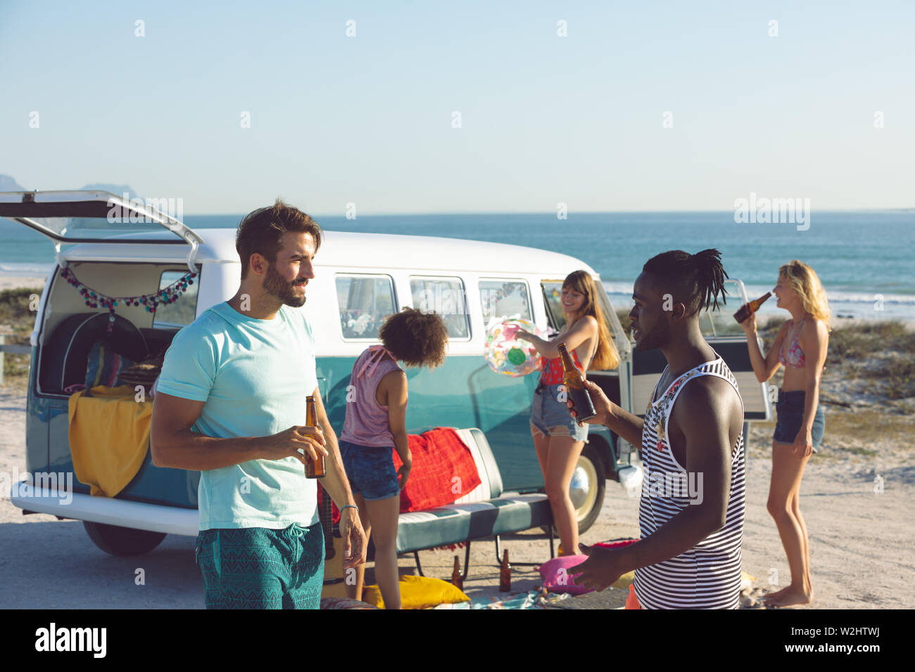 Group of friends having fun near camper van at beach Stock Photo - Alamy
