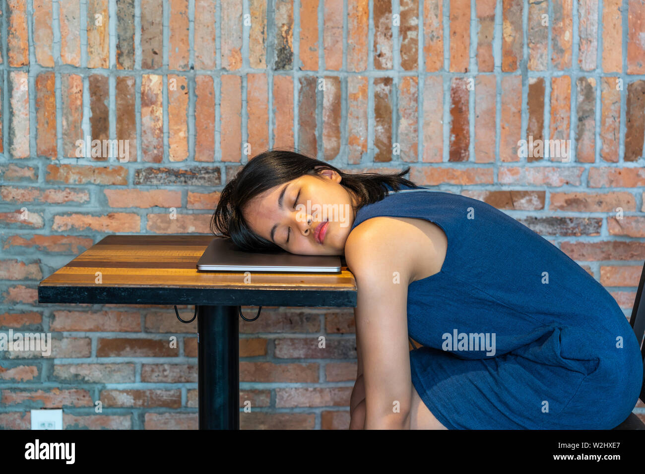 Restless woman falling asleep on laptop at rustic brick wall Stock ...