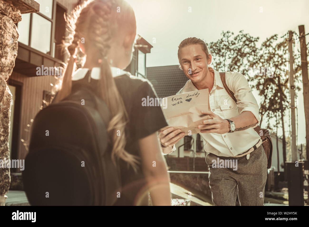 Smiling good-looking young father in white shirt presenting package ...