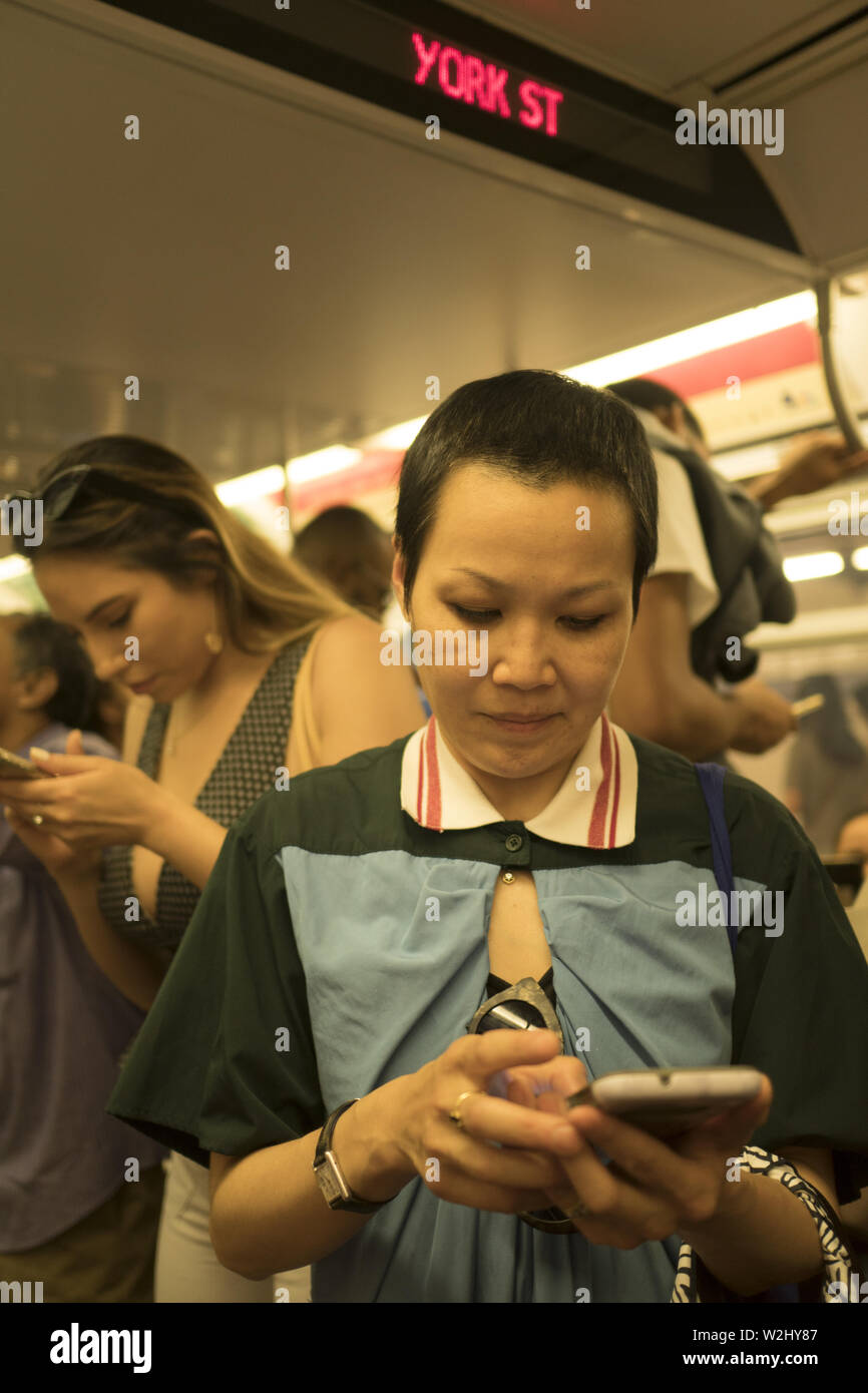 People riding subway trains use their cell phones, taking advantage of ...