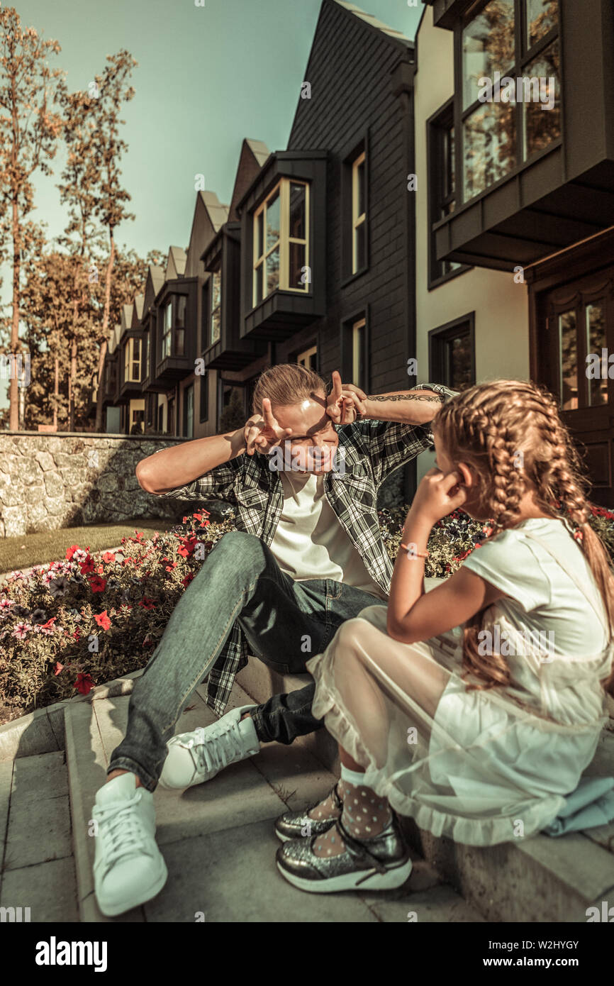 Pleasant childish father in comfortable outfit playing with long-haired ...