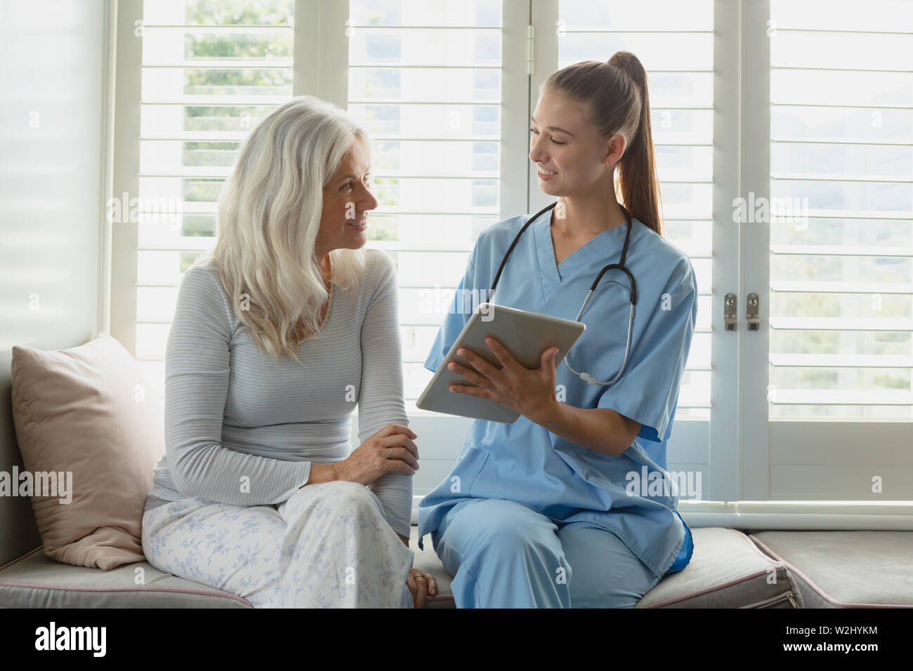 Active senior woman and female doctor using digital tablet on window ...