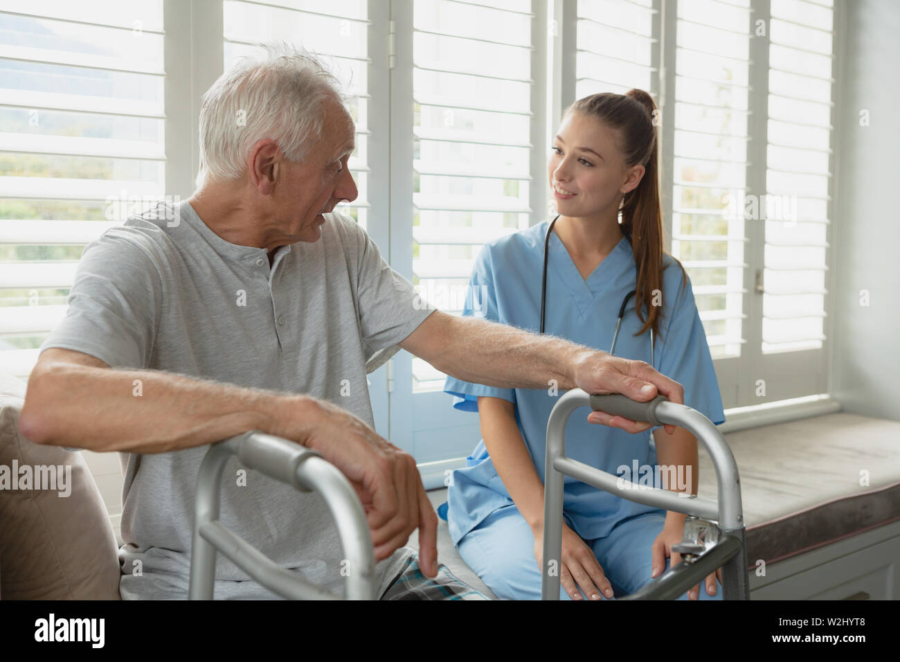Female doctor interacting with active senior man on window seat Stock ...