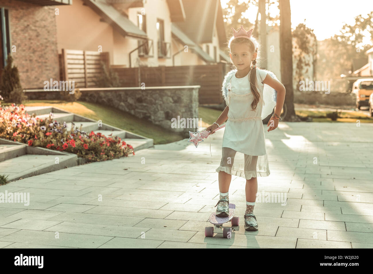 Resolute young lady in white dress riding on a skateboard Stock Photo ...