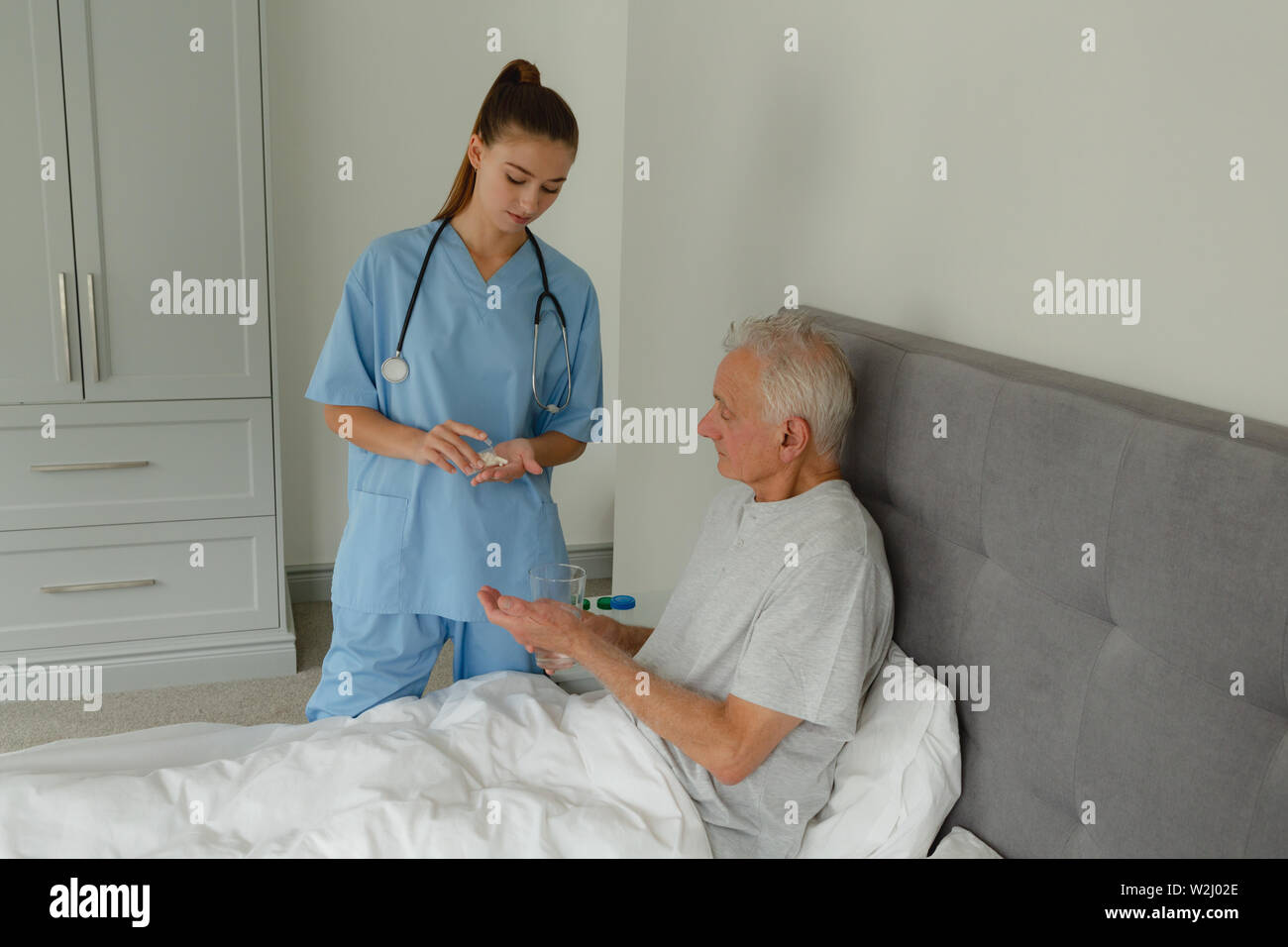 Female doctor giving medicine to active senior patient in bedroom Stock ...