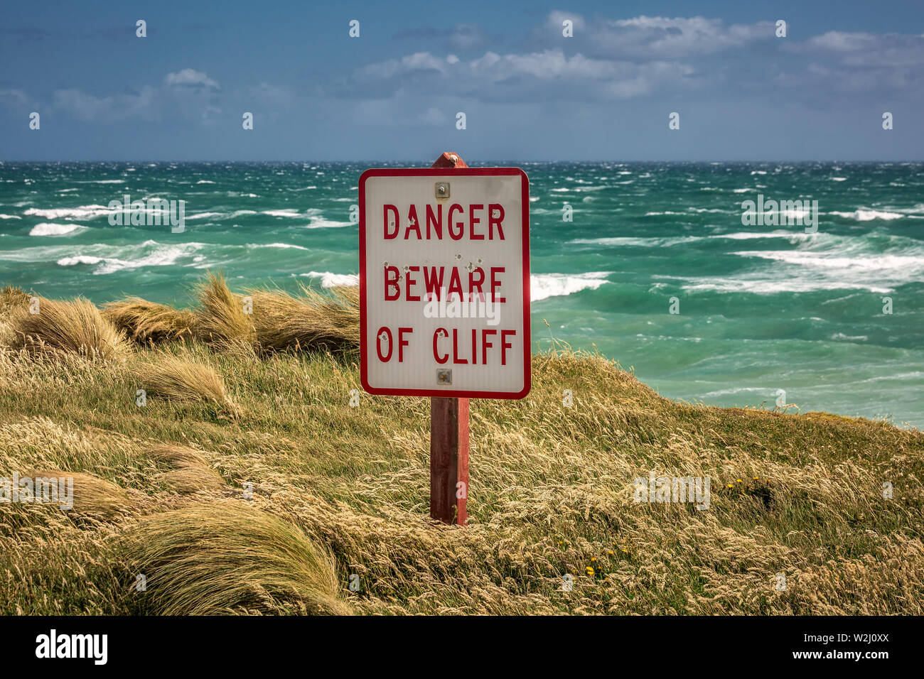 Danger sign at coast with huge waves near Bluff, New Zealand Stock ...
