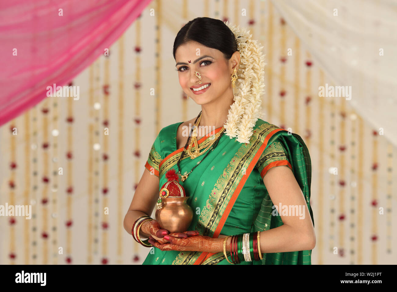 Indian young woman holding a kalash and smiling Stock Photo - Alamy