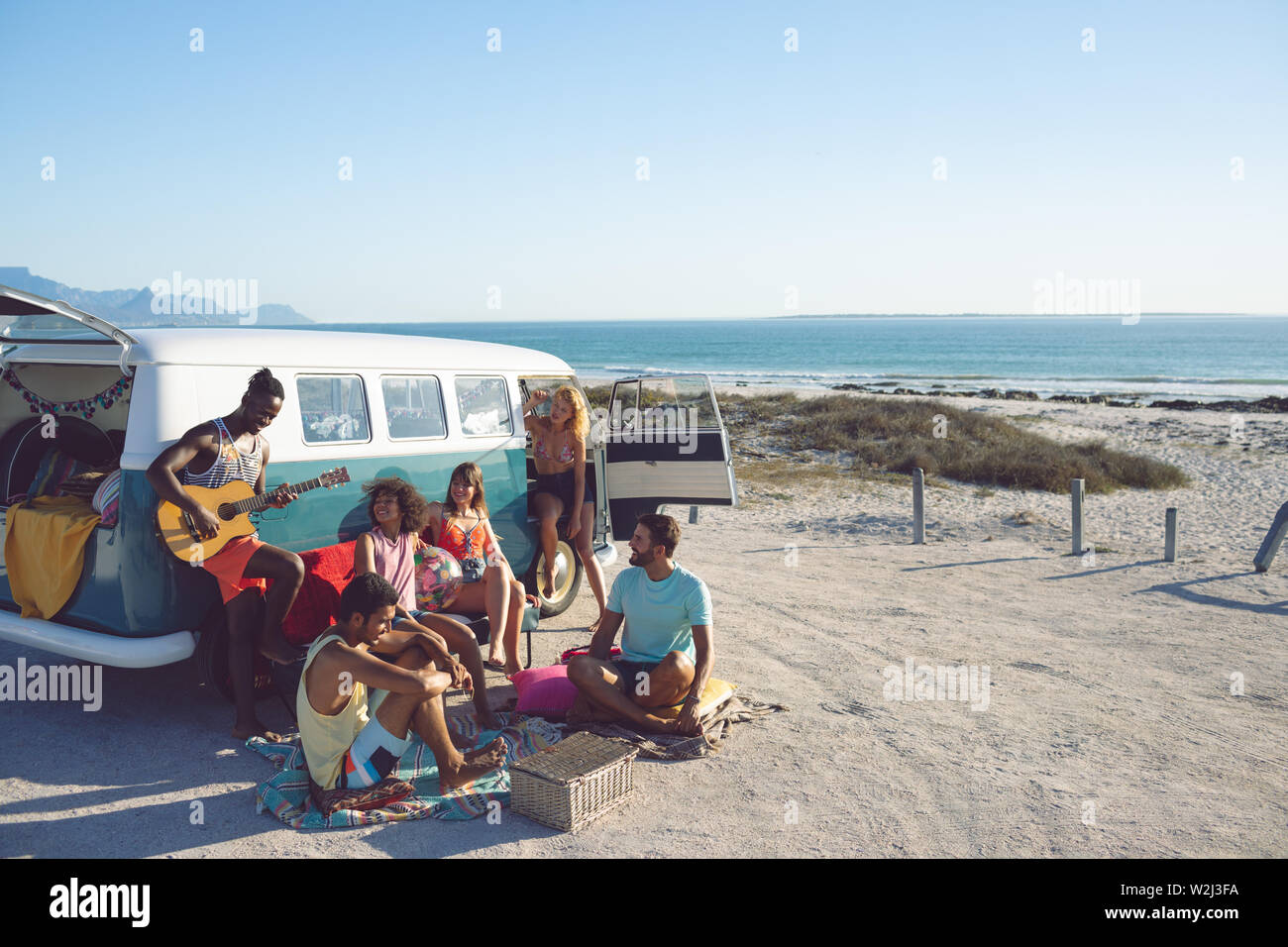 Group of friends having fun near camper van at beach Stock Photo - Alamy