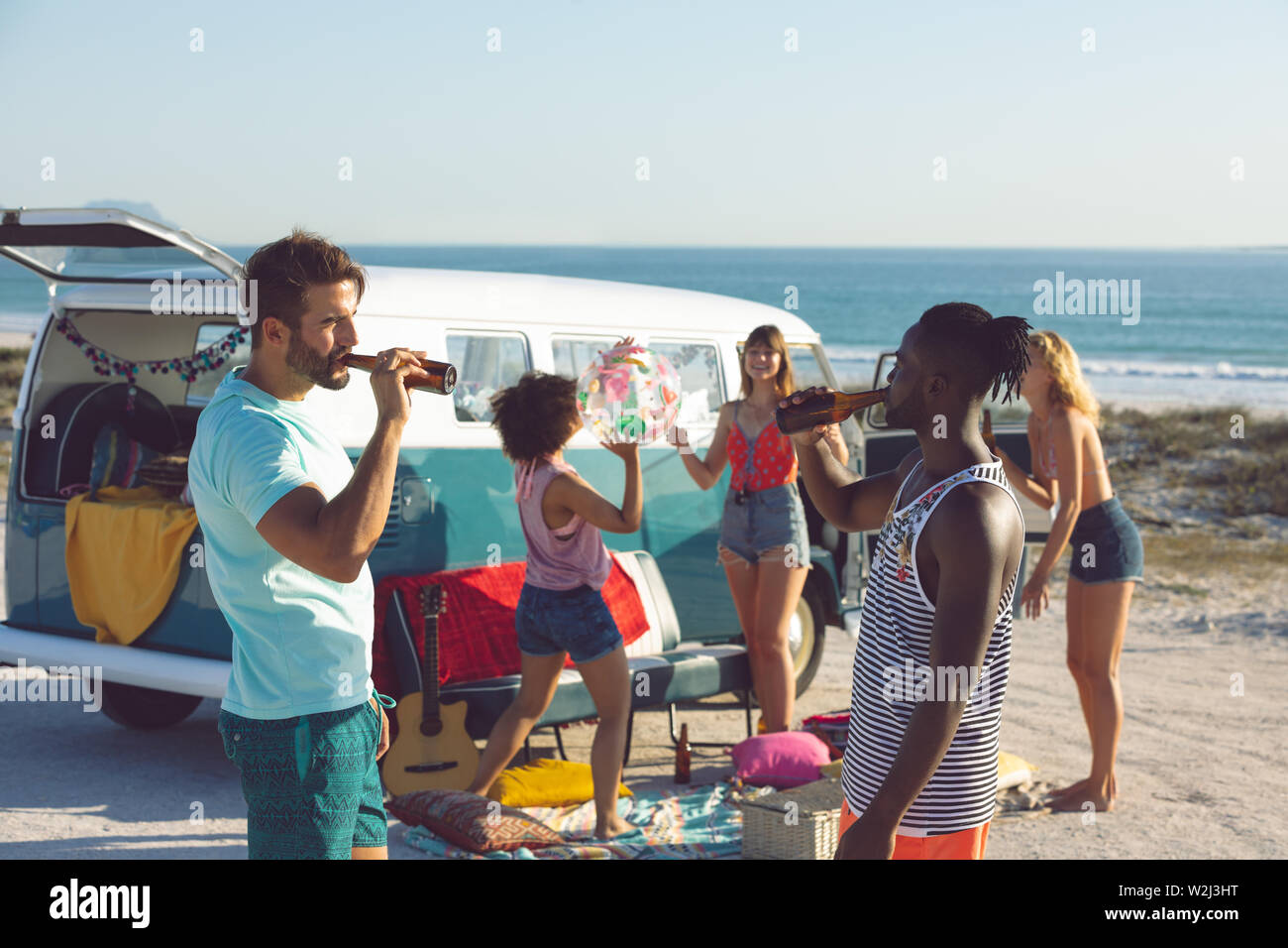 Group of friends having fun near camper van at beach Stock Photo - Alamy