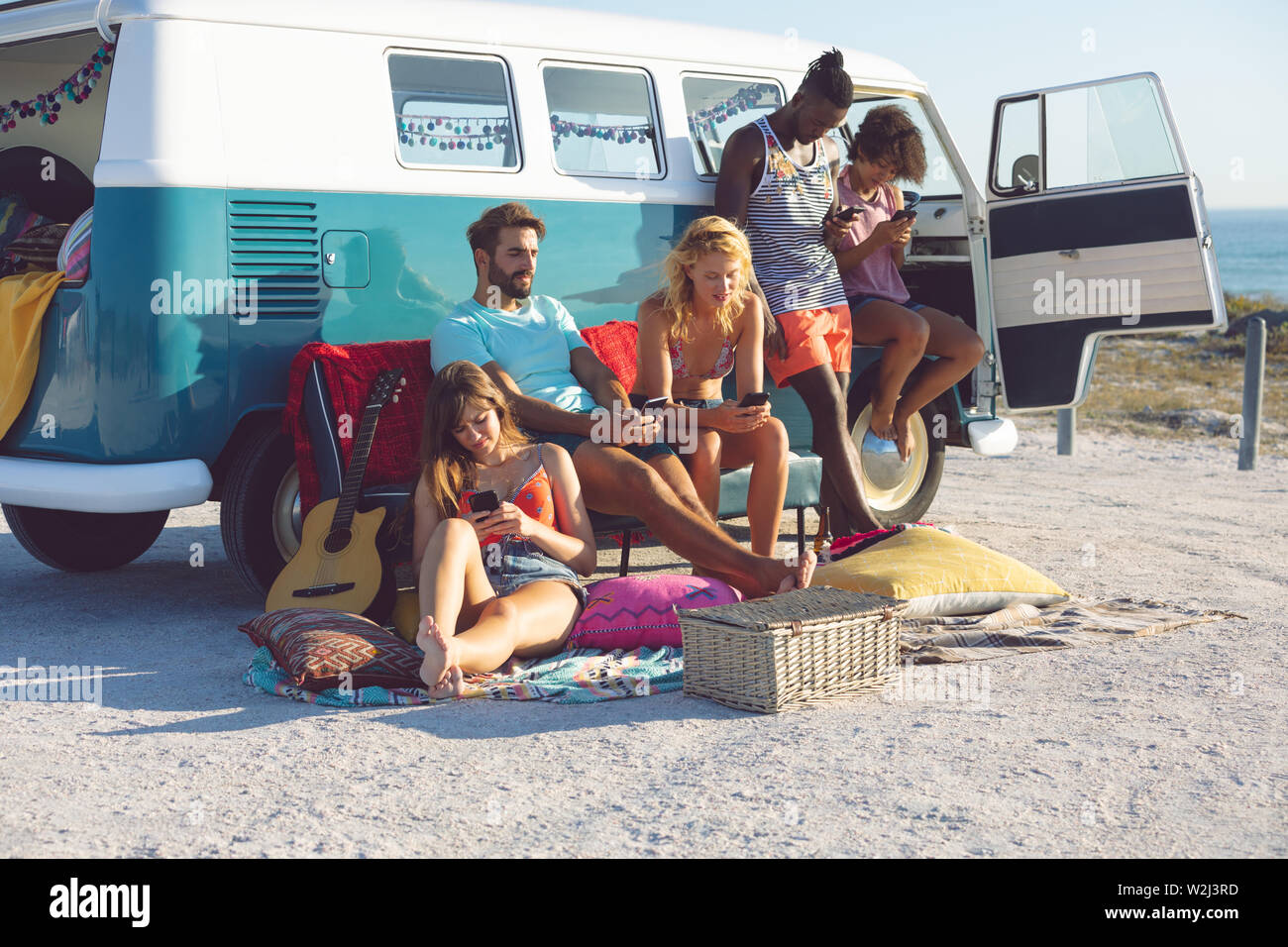 Group of friends using mobile phone near camper van at beach Stock ...