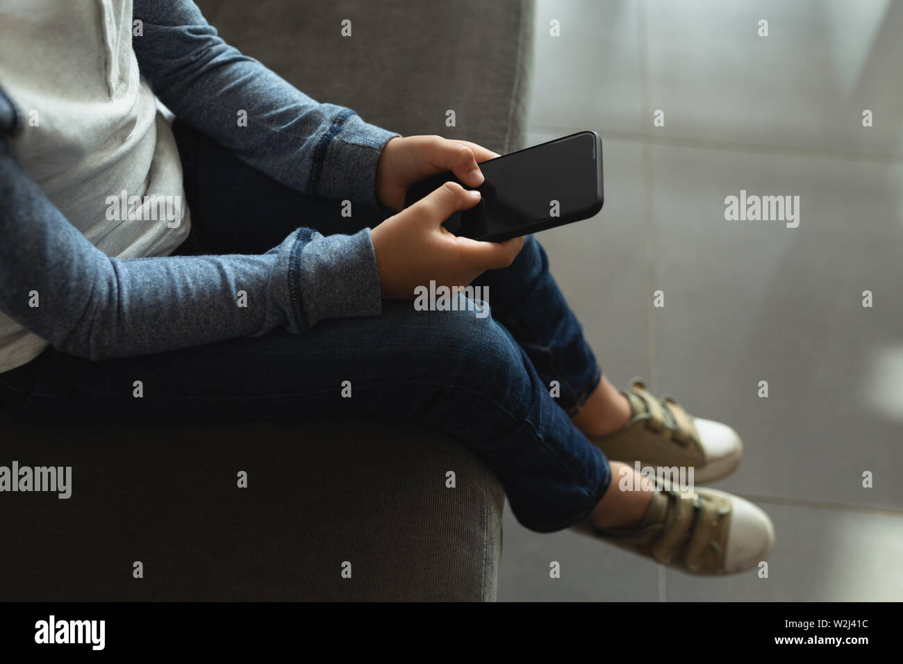 Boy using mobile phone in the lobby at hospital Stock Photo - Alamy