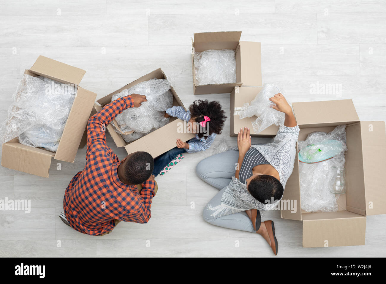 Family unpacking cardboard boxes in living room Stock Photo - Alamy