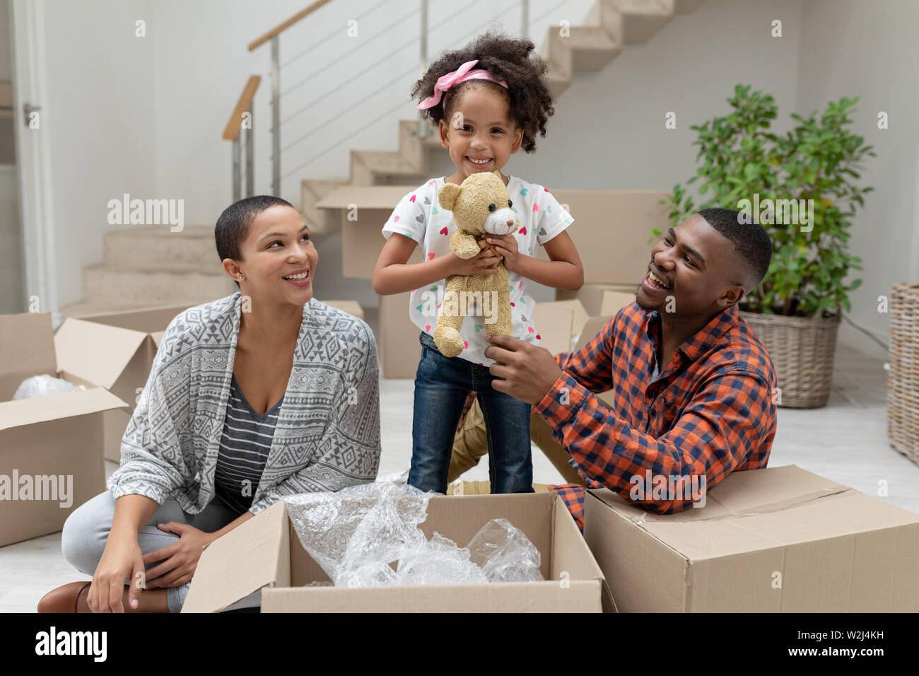 Family unpacking cardboard boxes in living room Stock Photo - Alamy