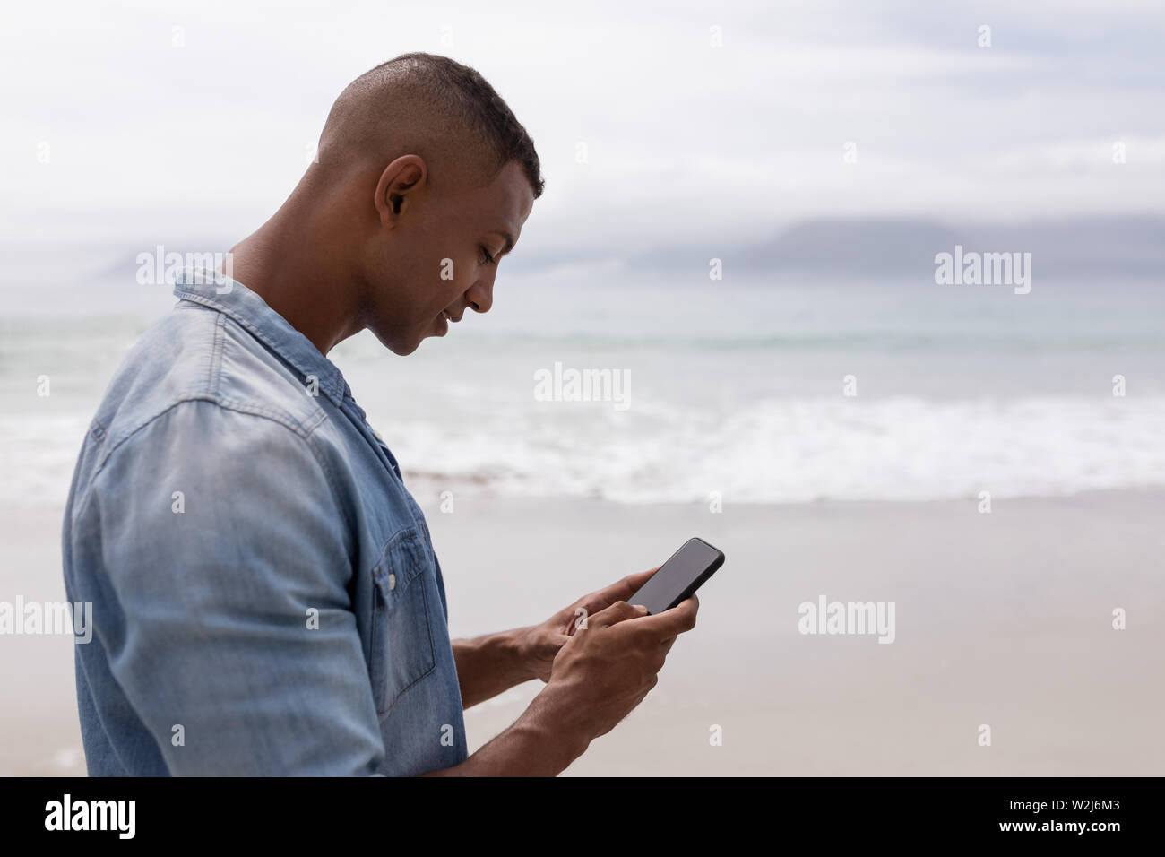 Man using mobile phone on the beach Stock Photo - Alamy