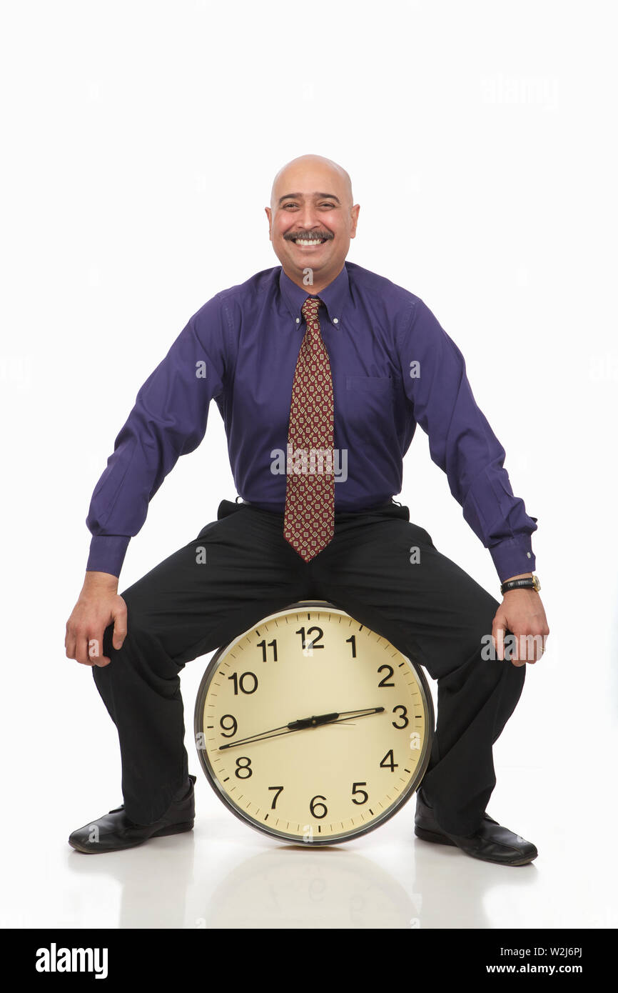 Portrait of a businessman sitting on a clock Stock Photo - Alamy