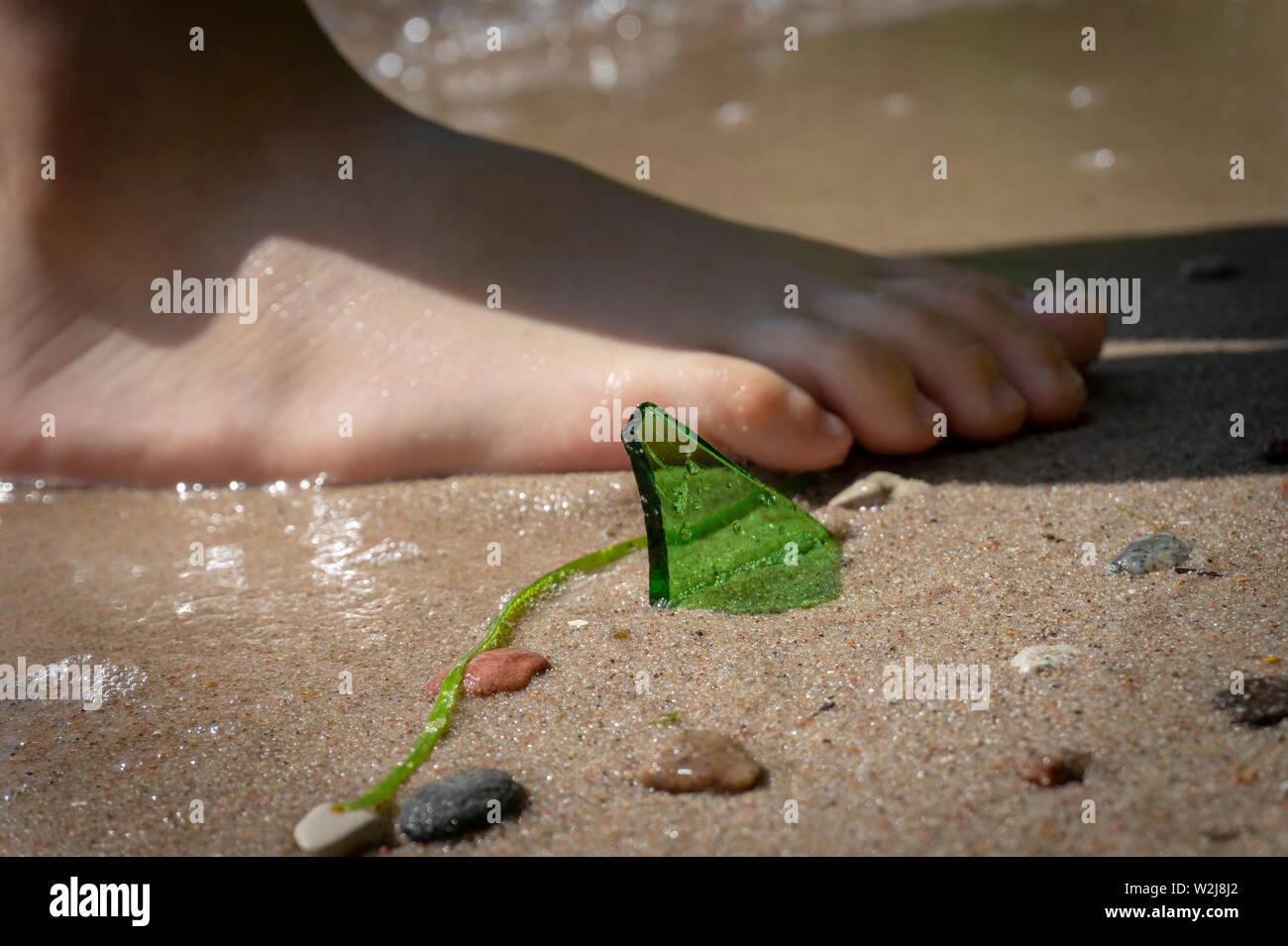 Danger of broken glass on a beach with a close up view of a shard of ...