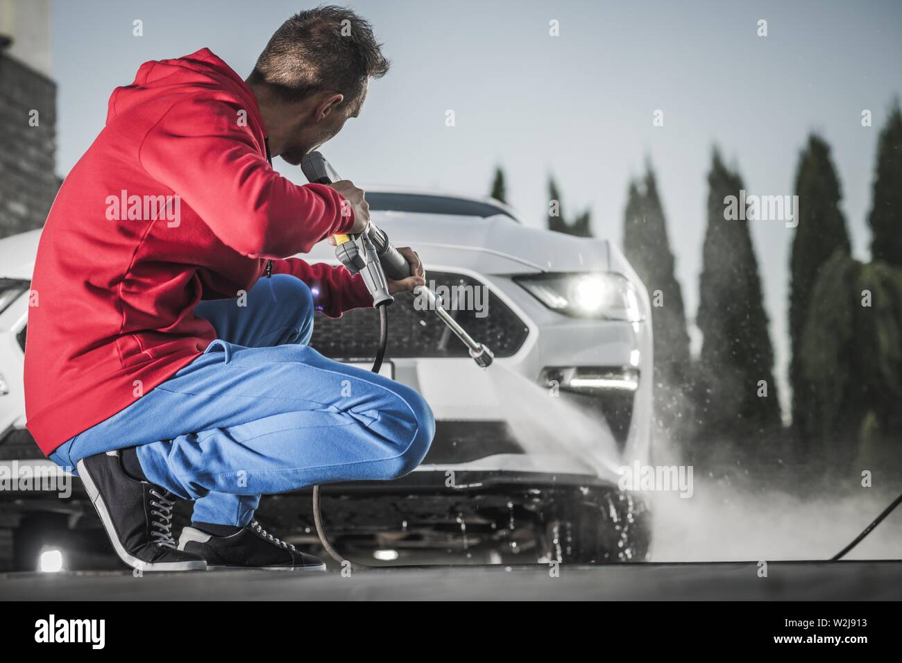 Caucasian Men with Pressure Washing Machine Washing His Modern Car on a ...