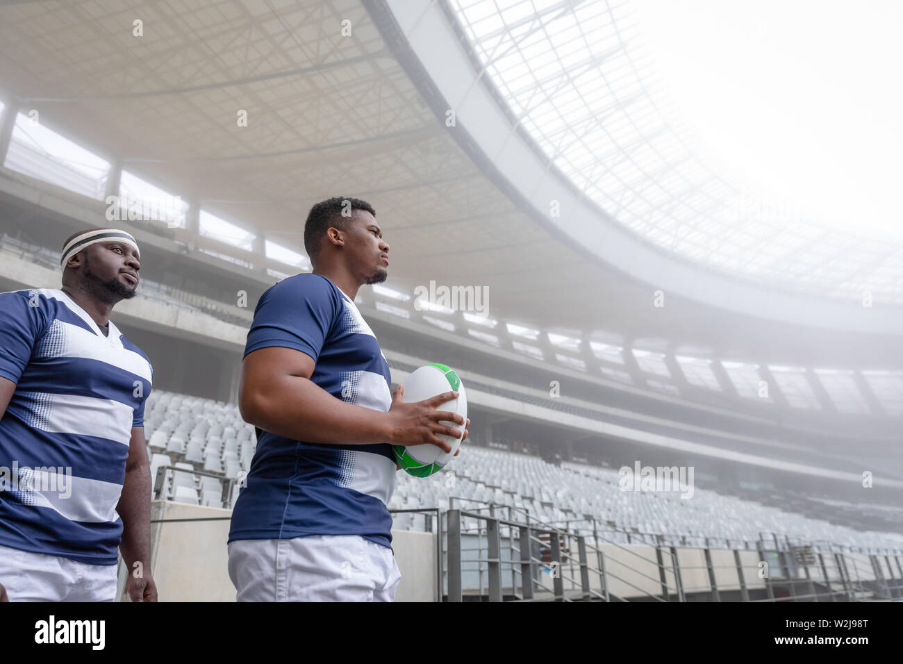 Diverse male rugby player standing in a row at the entrance of stadium ...