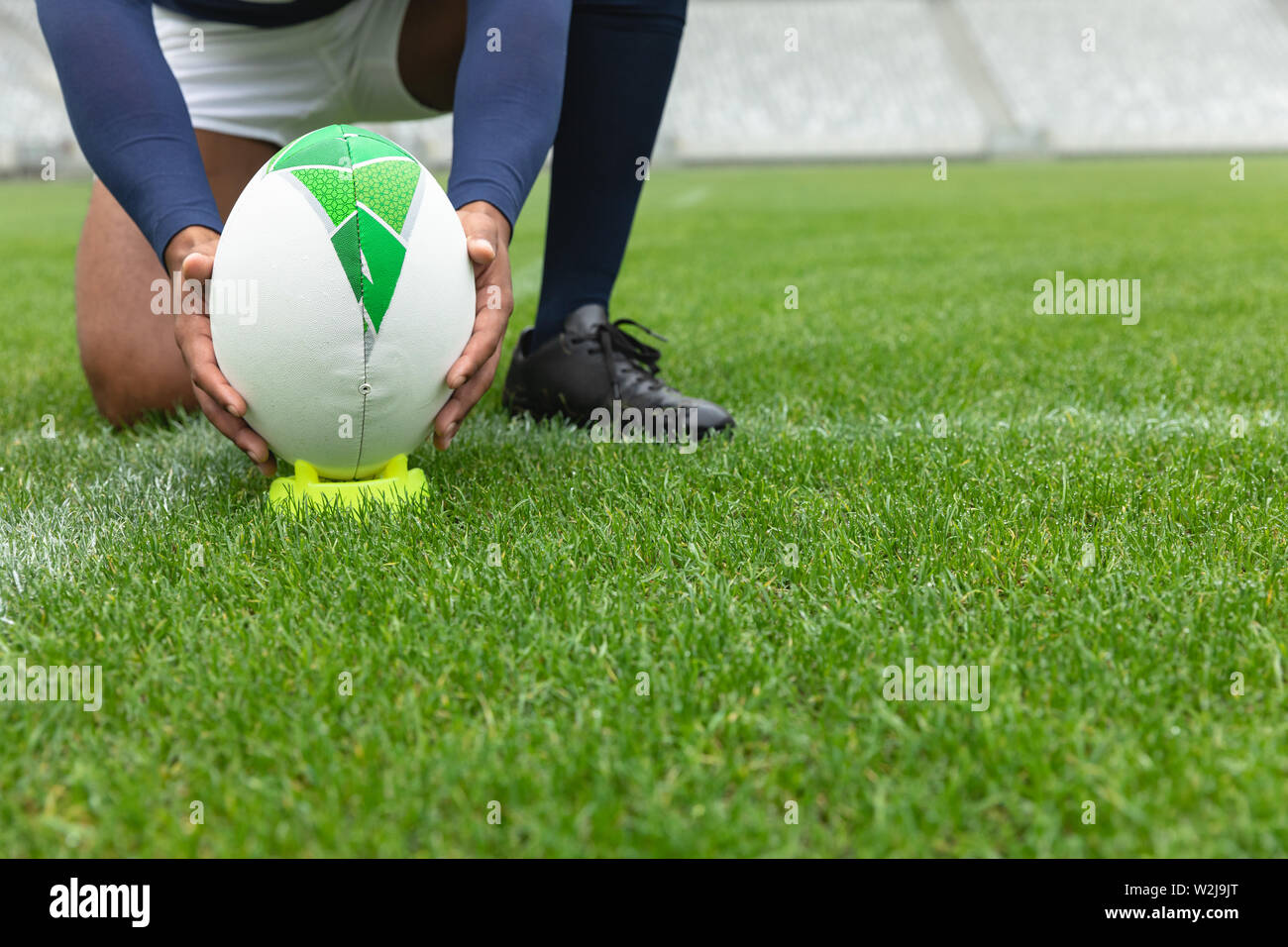 African American male rugby player placing rugby ball on a stand in ...