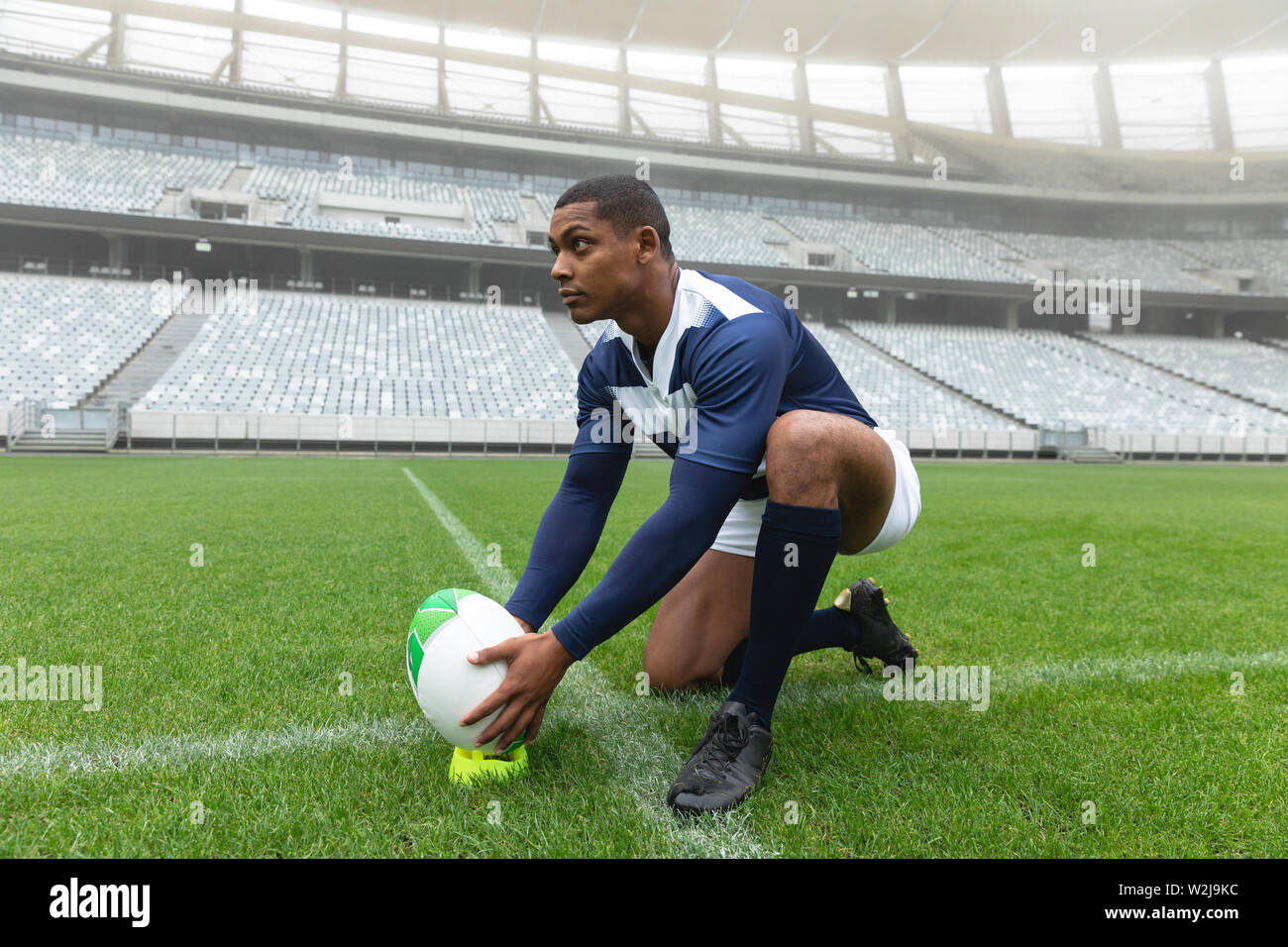 African American male rugby player placing rugby ball on a stand in ...