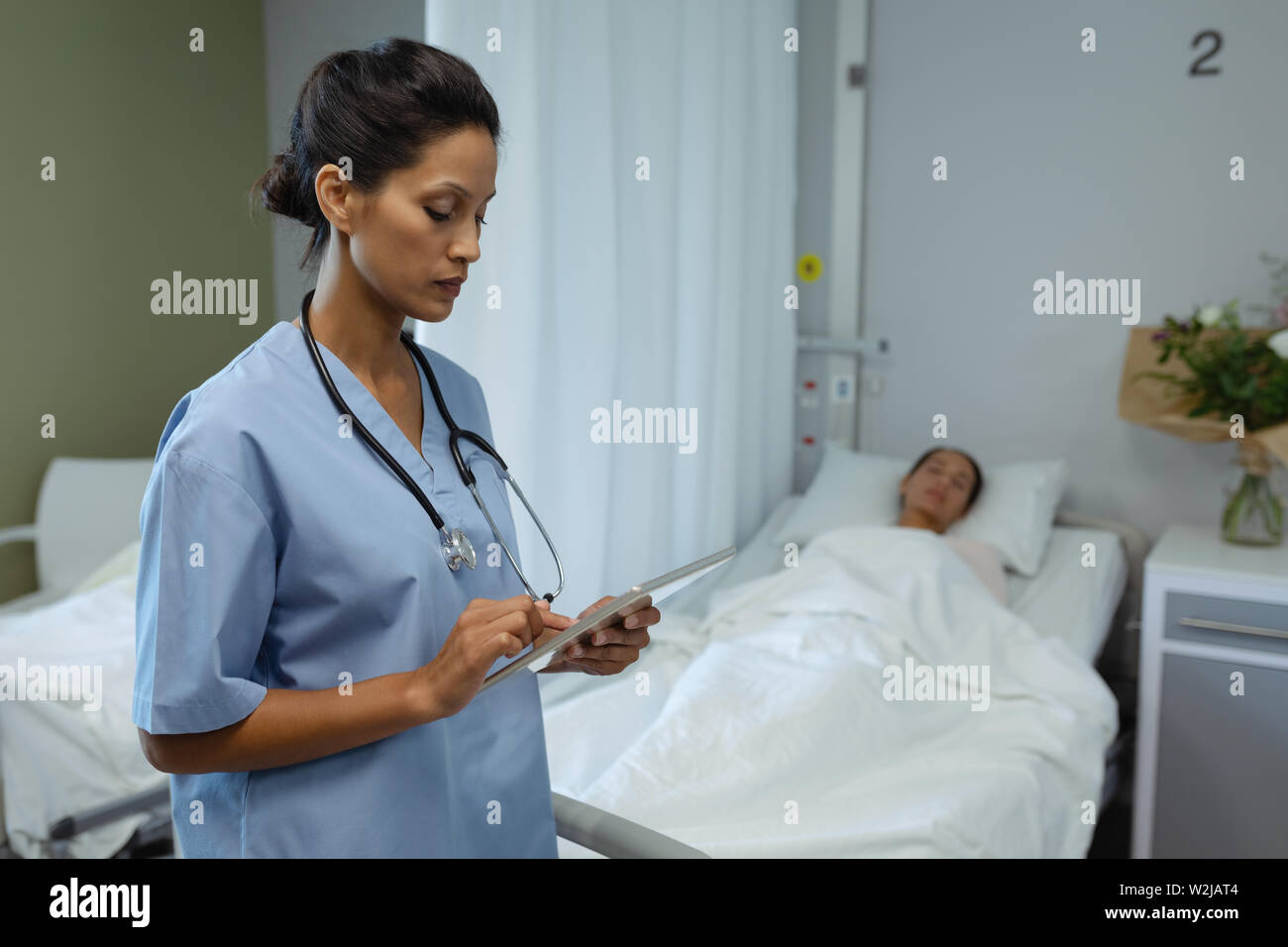 Female doctor using digital tablet while patient sleeping in bed in the ...