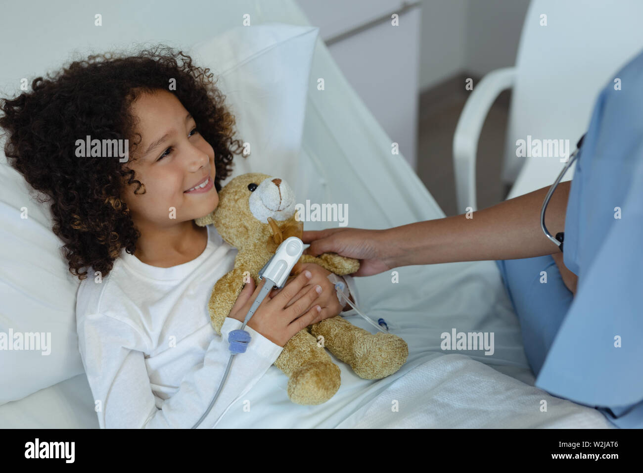 Female doctor giving teddy bear to child patient in the ward Stock ...