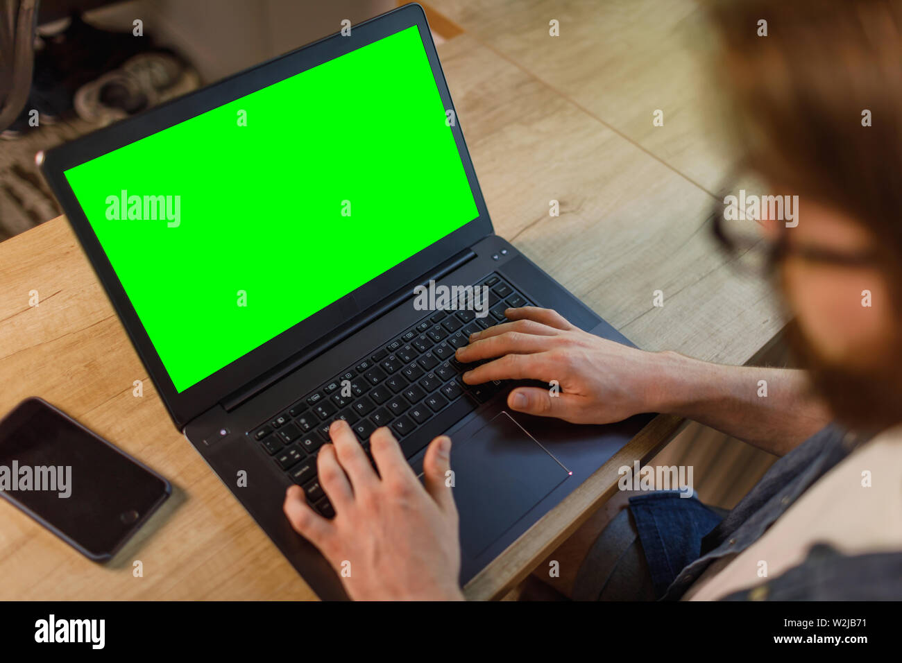 Over the shoulder shot of a man typing on a computer laptop with a key ...