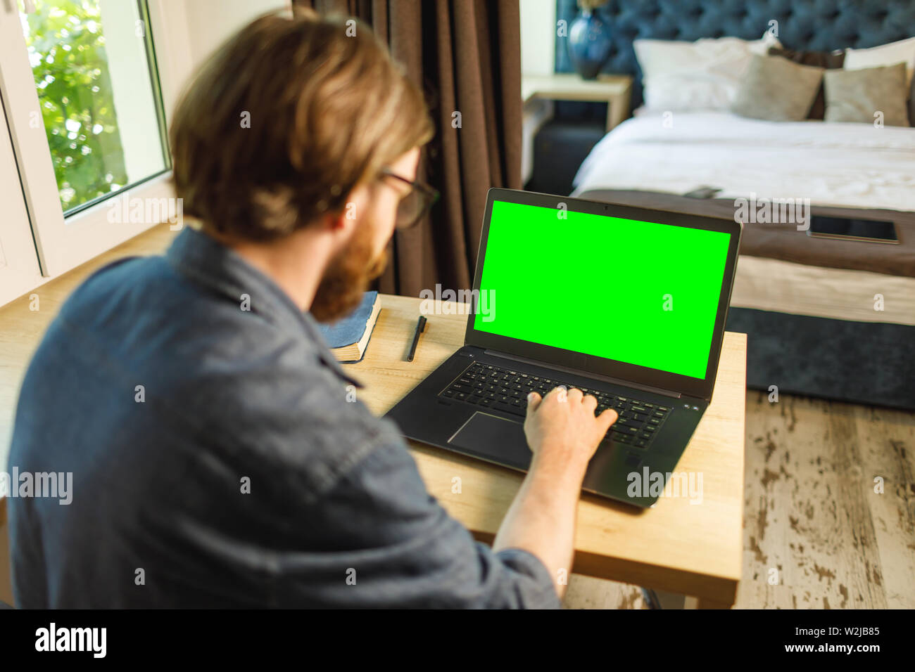 Bearded man using laptop, workplace at home with green screen Stock ...