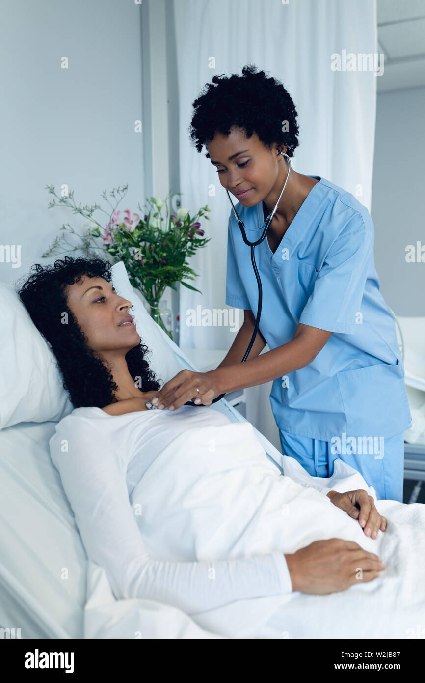 Female doctor examining female patient with stethoscope in the ward ...